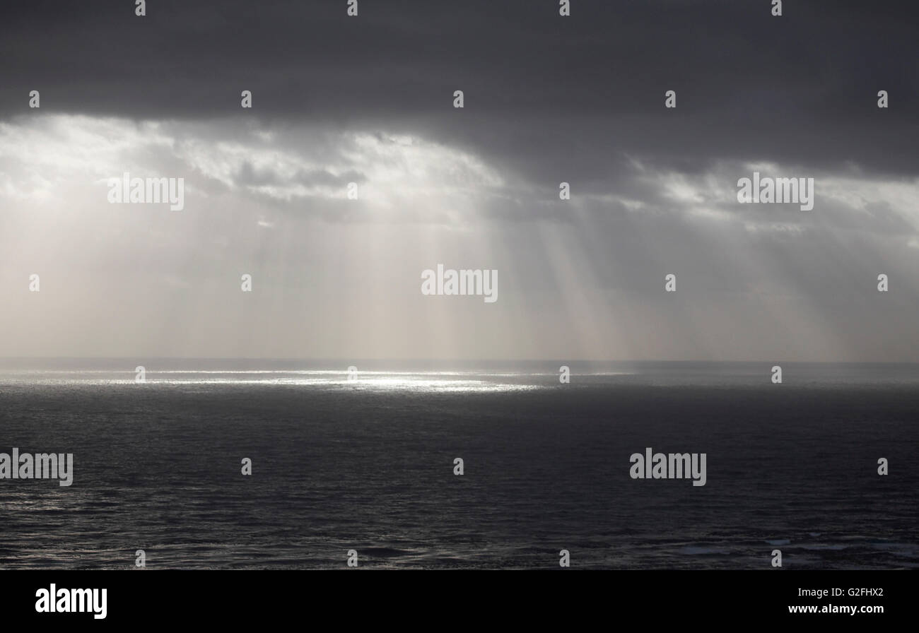 Sun Rays Reflected on Ocean Through Gray Clouds Stock Photo - Alamy