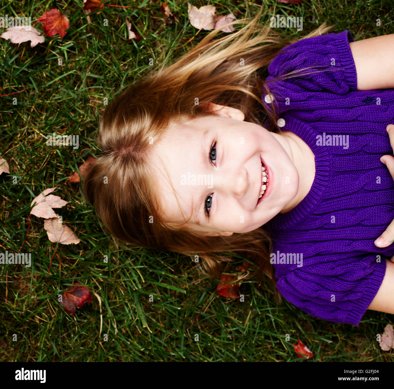 Smiling Young Girl Laying on Ground Stock Photo - Alamy