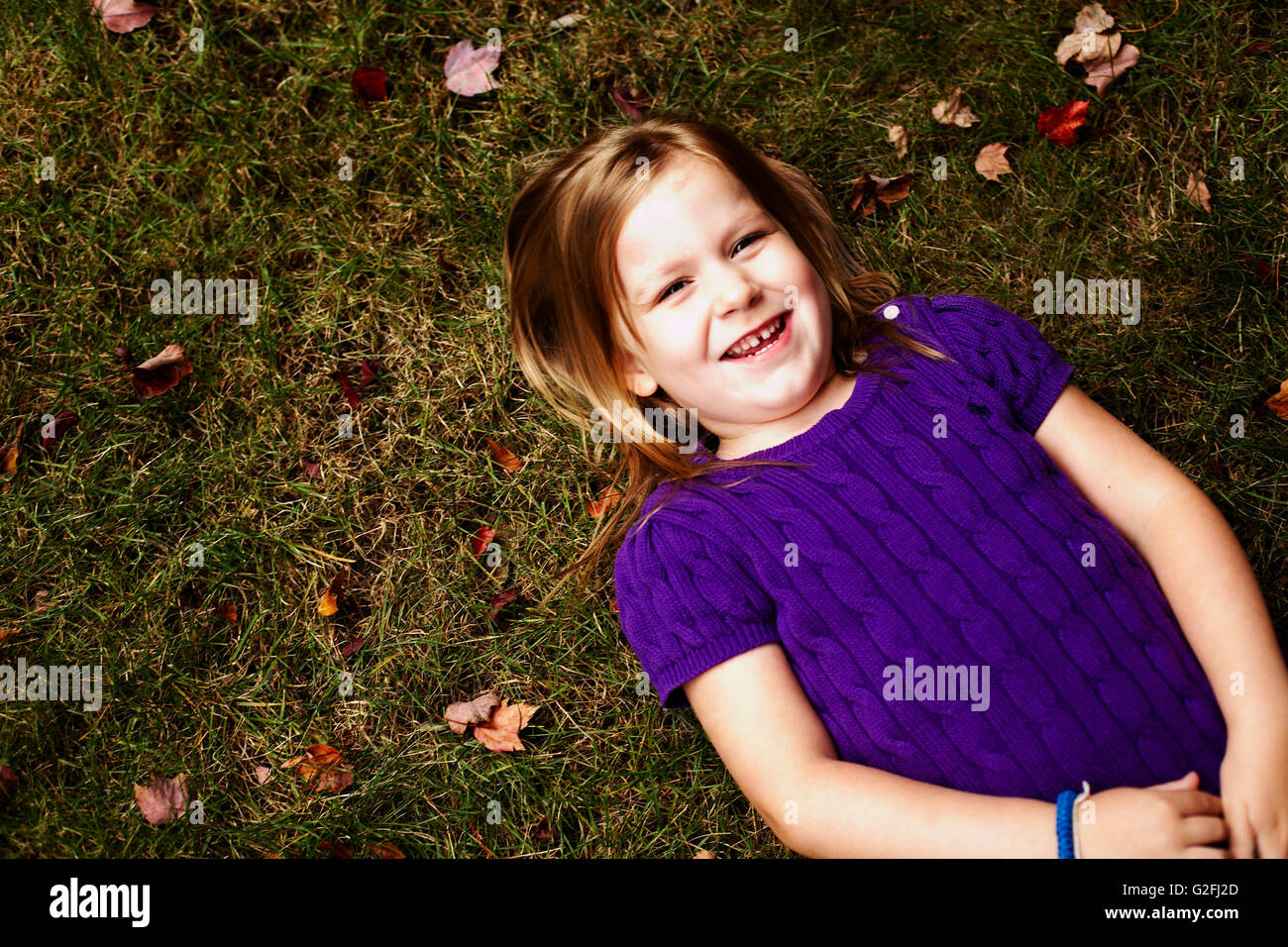 Young Smiling Girl Laying on Ground Stock Photo - Alamy