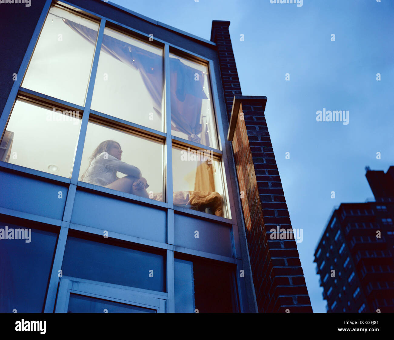 View from Outside of Young Adult Woman Gazing out Window at Night, Low ...