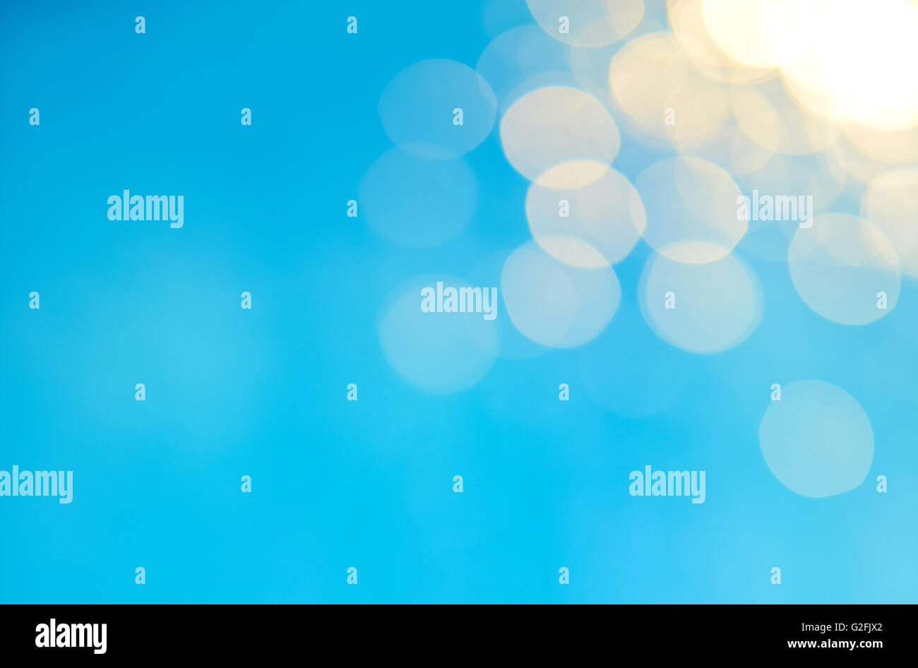 Soft focus bokeh light effects over a rippled, blue water background in ...