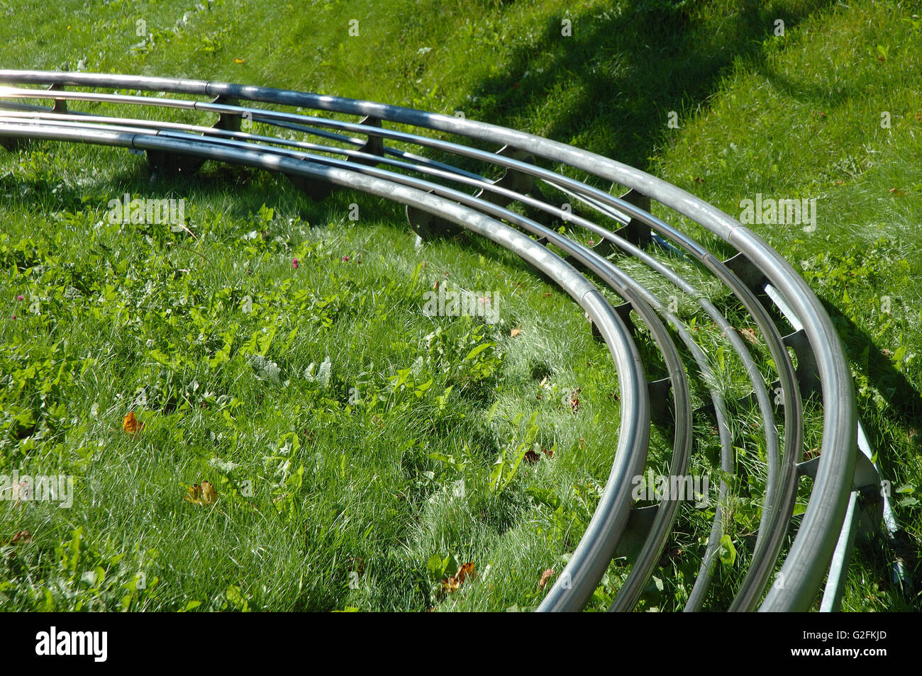 Roller coaster tracks turn above green grass Stock Photo - Alamy