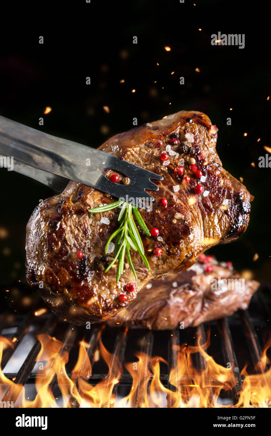 Beef steak on grill with black background Stock Photo - Alamy