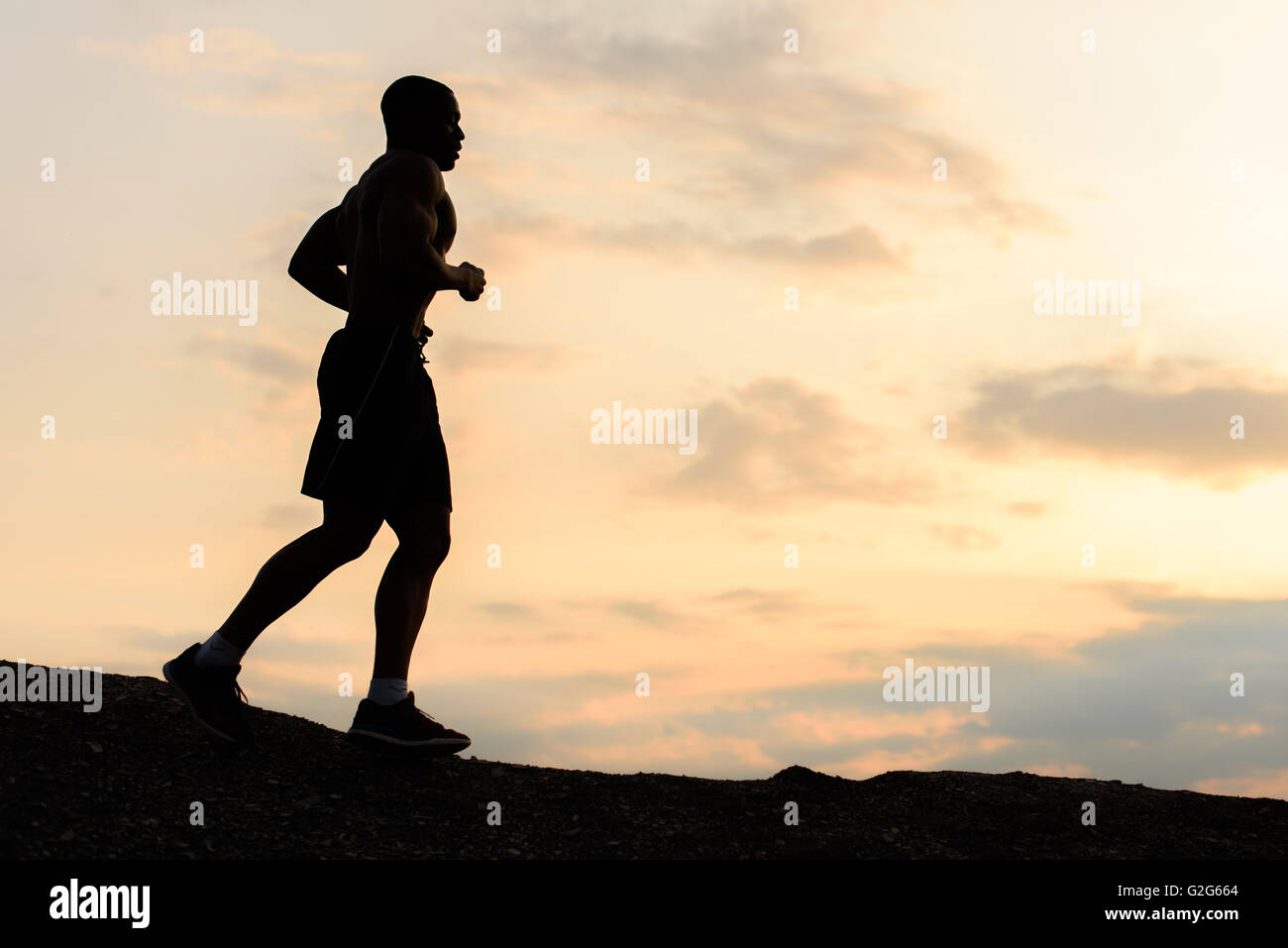 Silhouette of african american athlete man jogging on sunset in ...