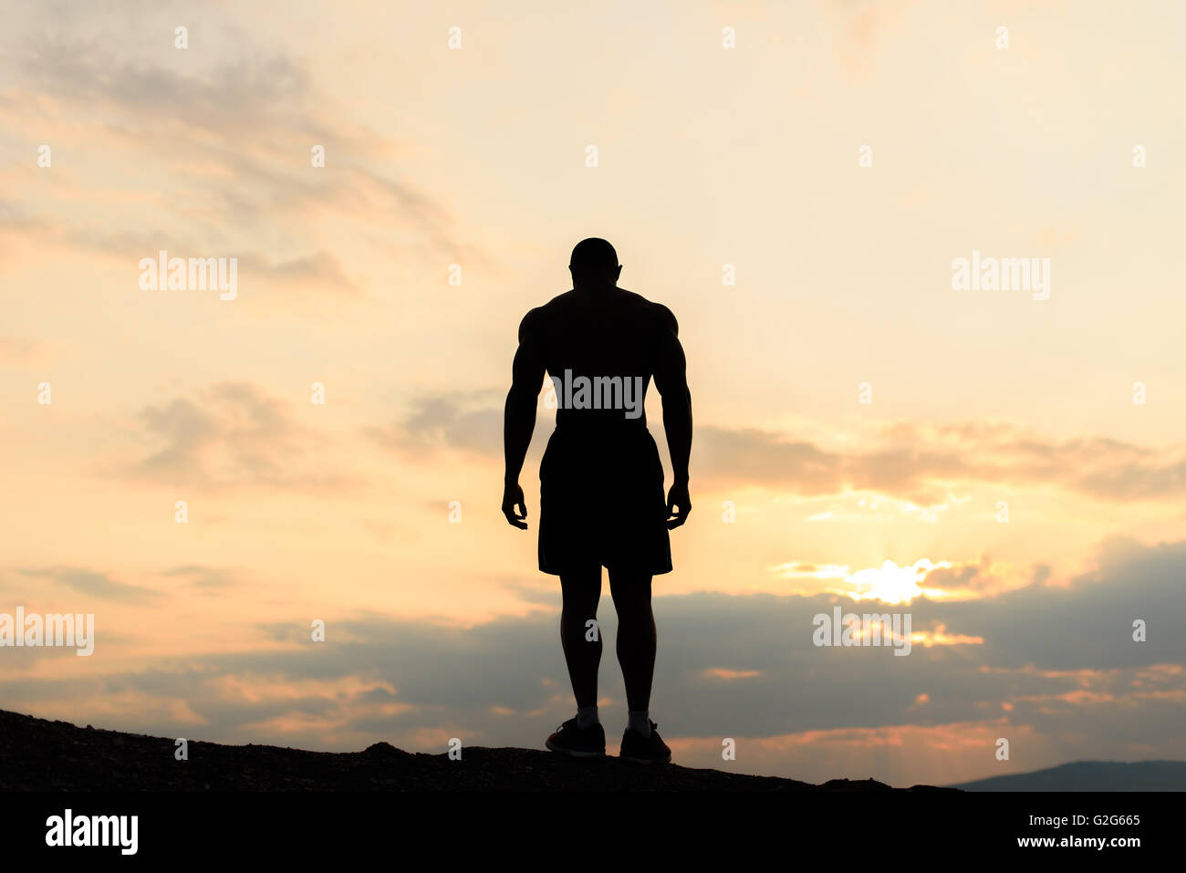 Back view on silhouette of bodybuilder posing at the sunrise or sunset ...