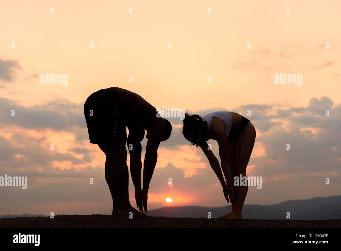 Silhouettes of fit mixed race couple stretching and training together ...