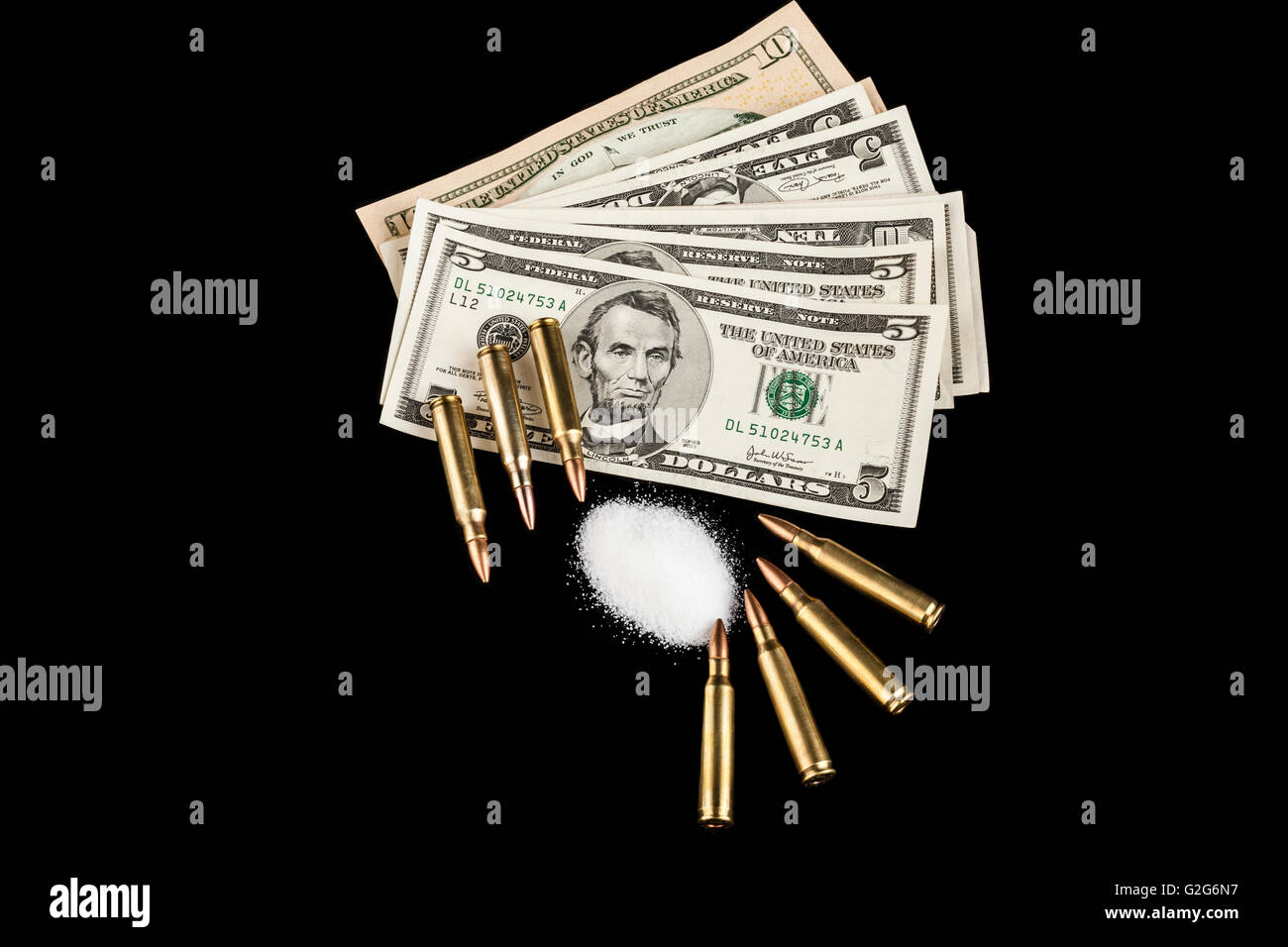 bullets on dollar banknotes with white drug powder on black background ...