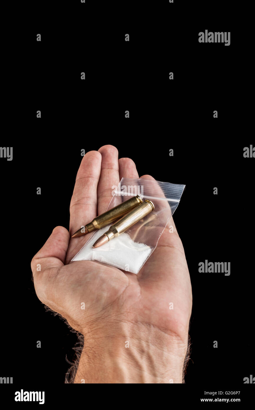 Rifle bullets close-up in hand on black background with a bag of white ...