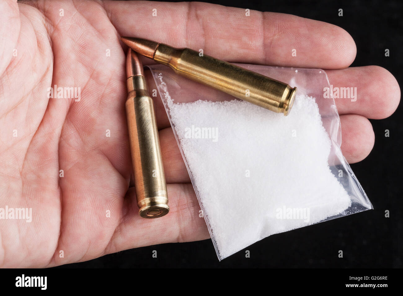 Rifle bullets close-up in hand on black background with a bag of white ...
