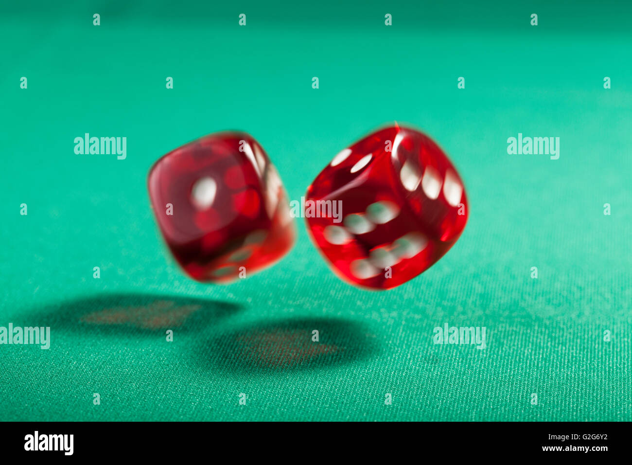 Pair of bouncing red dice blured on green background Stock Photo - Alamy