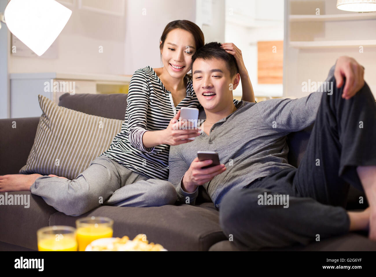 Young couple using smart phones on living room sofa Stock Photo - Alamy