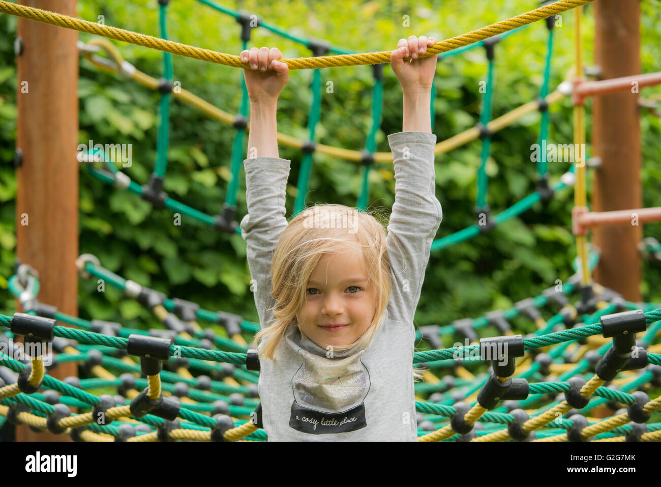 Portrait of Happy little girl climbing on a rope playground outdoor ...