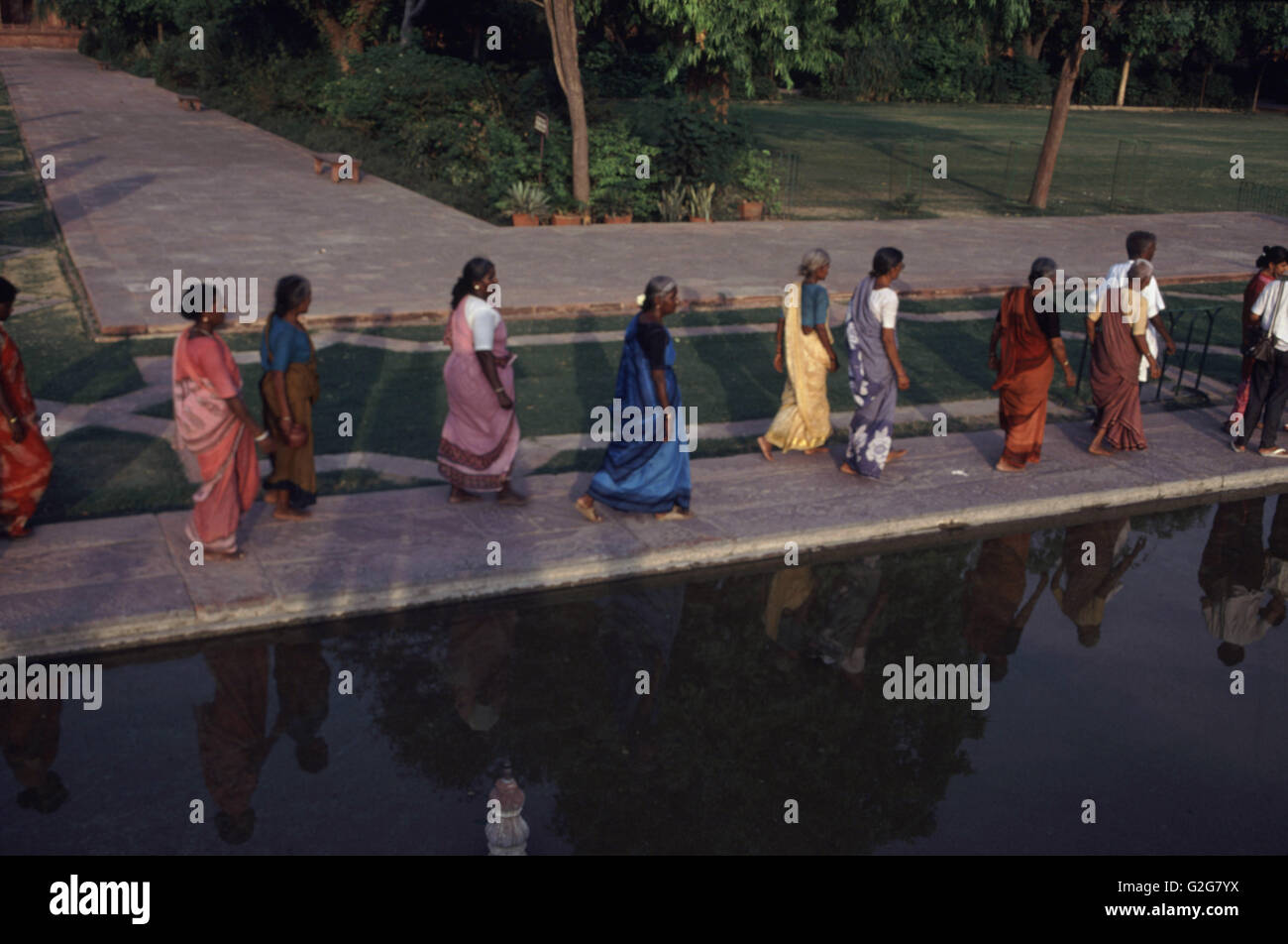 Women dressed in traditional clothes walking along the pool in front of ...