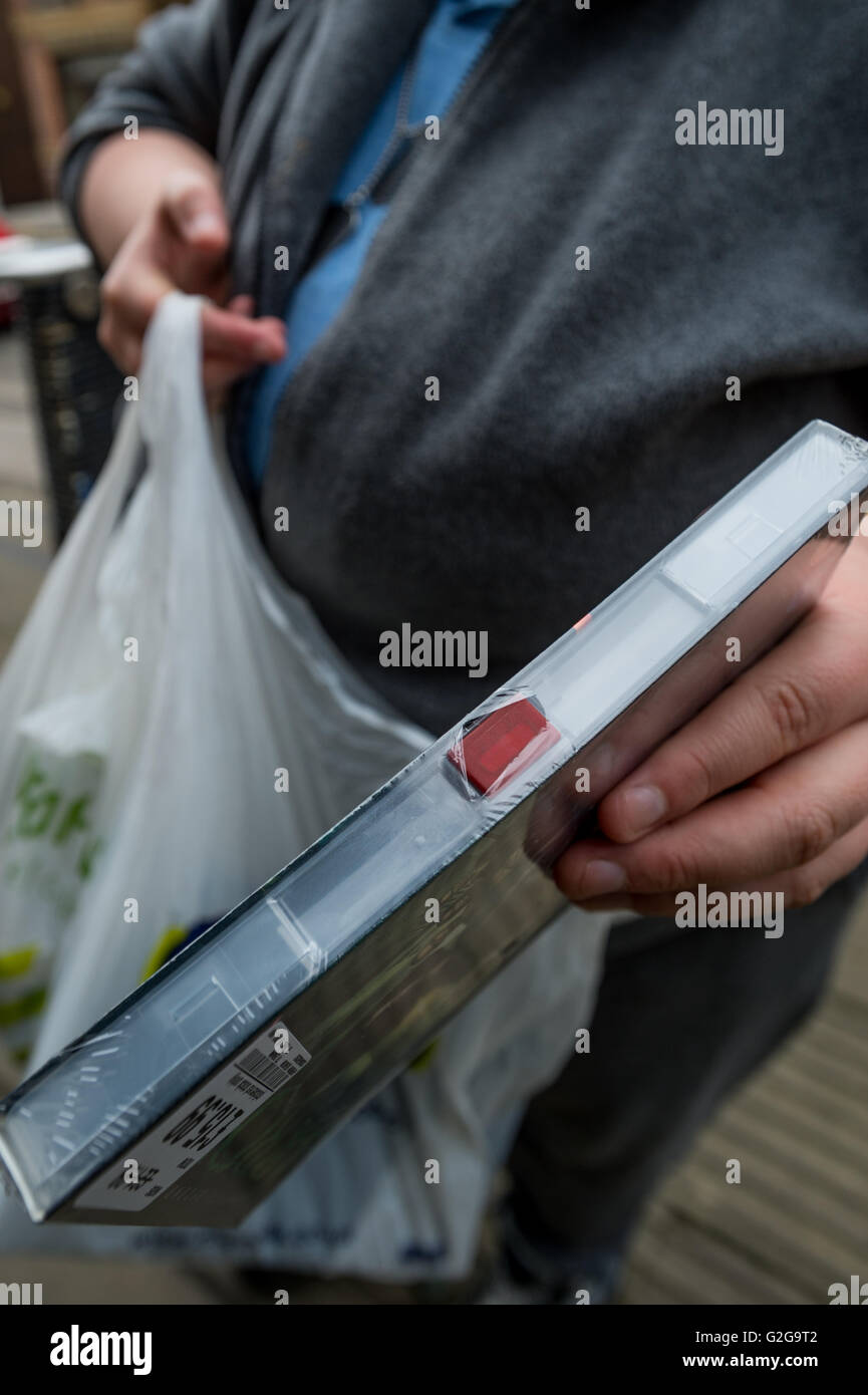 Shoplifter starts to remove security tag from a stolen DVD Stock Photo ...