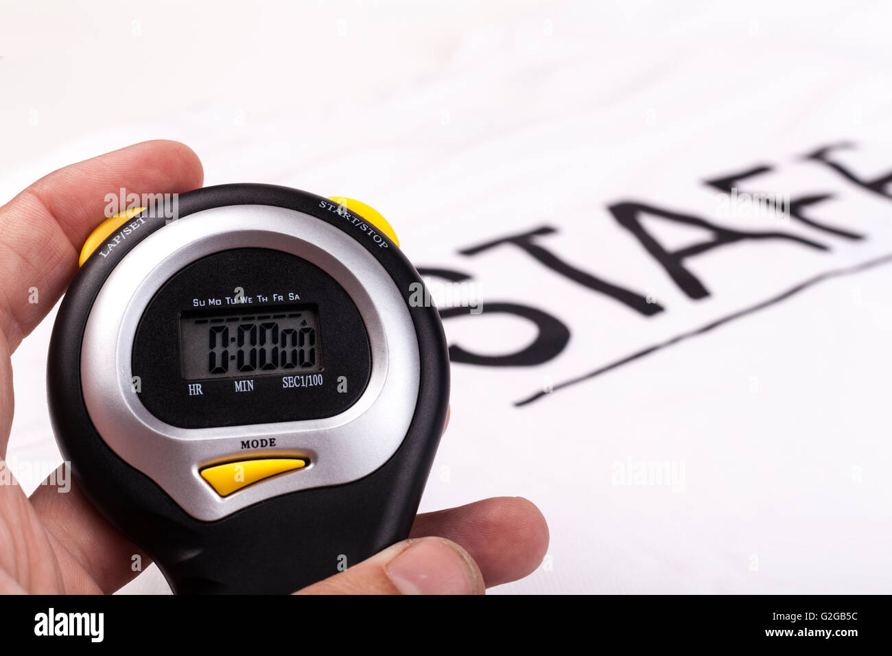 Black digital stopwatch held in hand on white background with staff ...