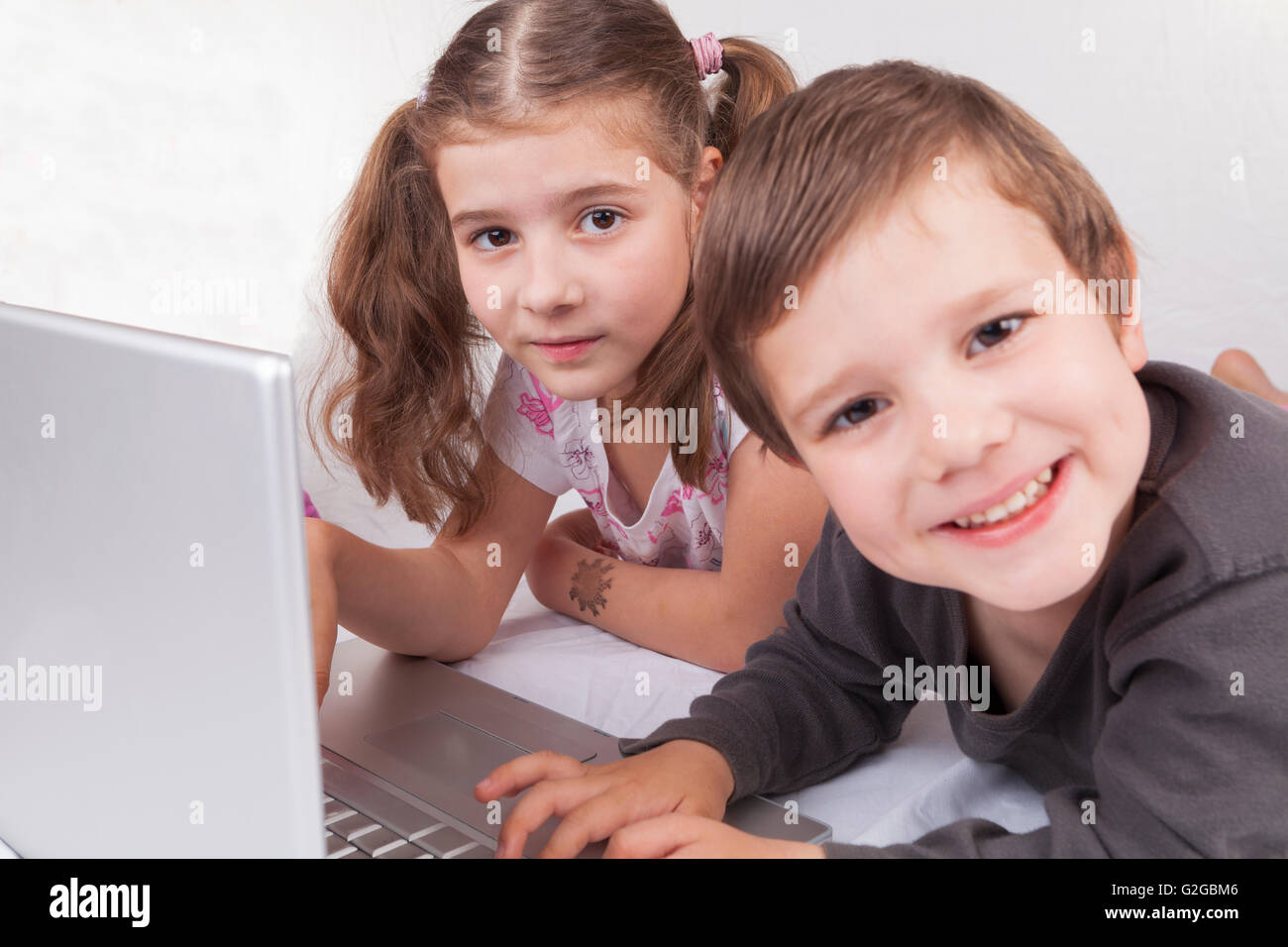 Boy and Girl playig with a silver color laptop Stock Photo - Alamy
