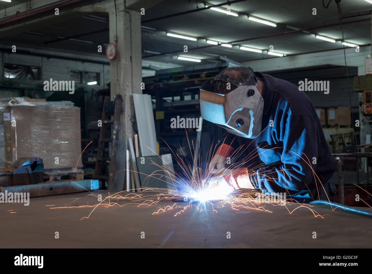 Single worker welding working in a steel factory with sparks flyig ...