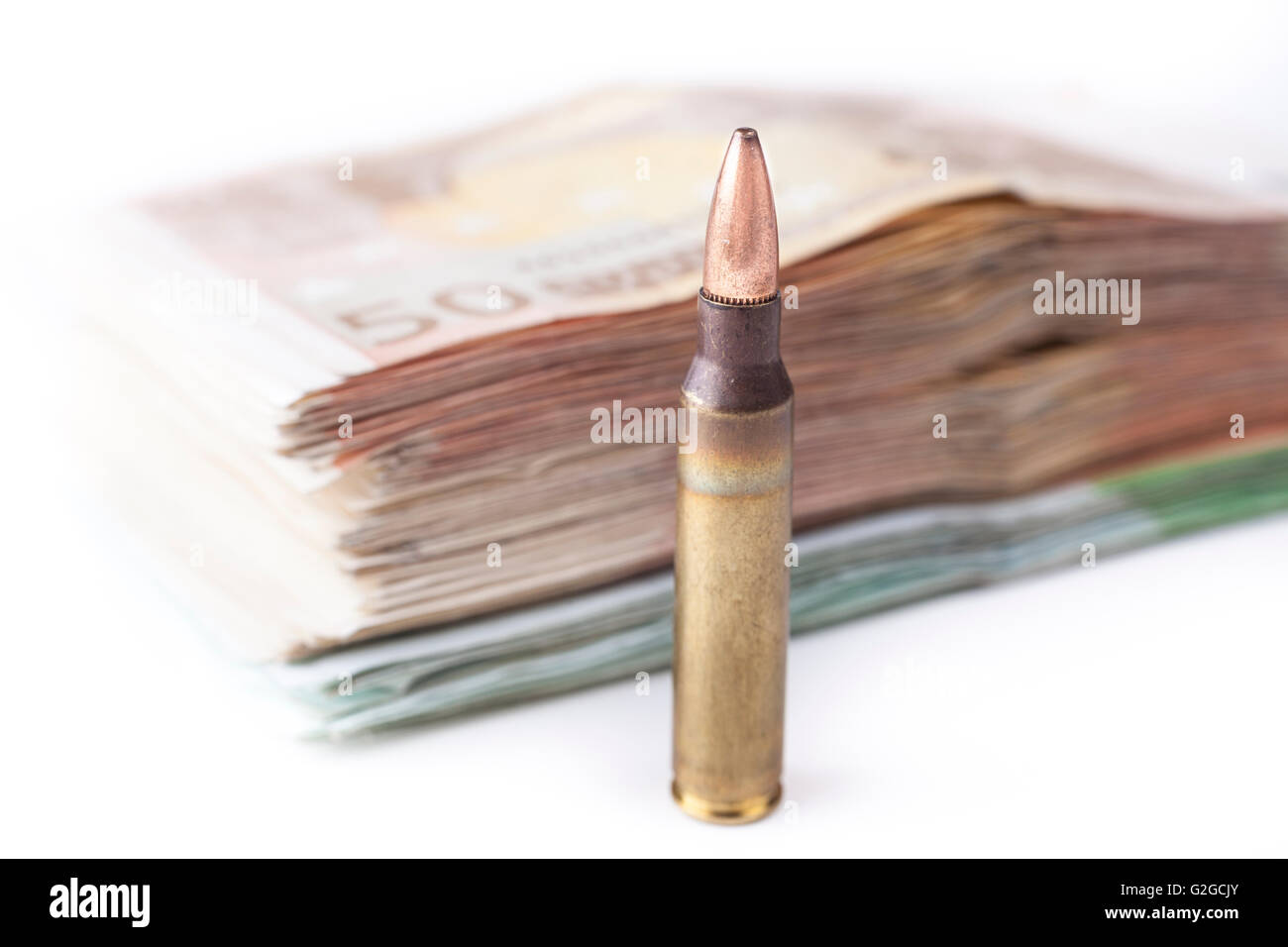 Single rifle bullet closeup with a pile of euro banknotes in the ...
