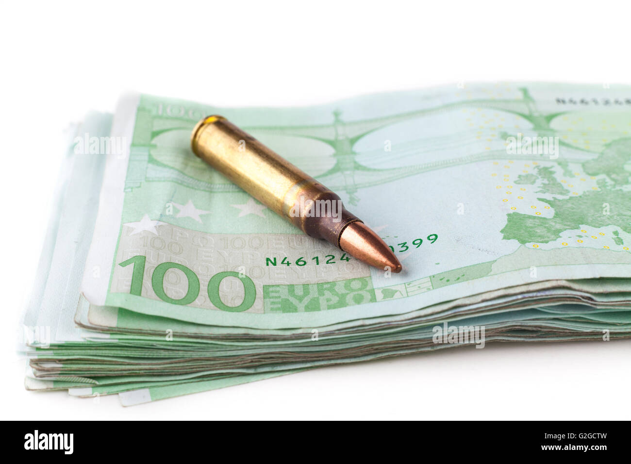 Single rifle bullet closeup with a pile of a hundred euro banknotes in ...