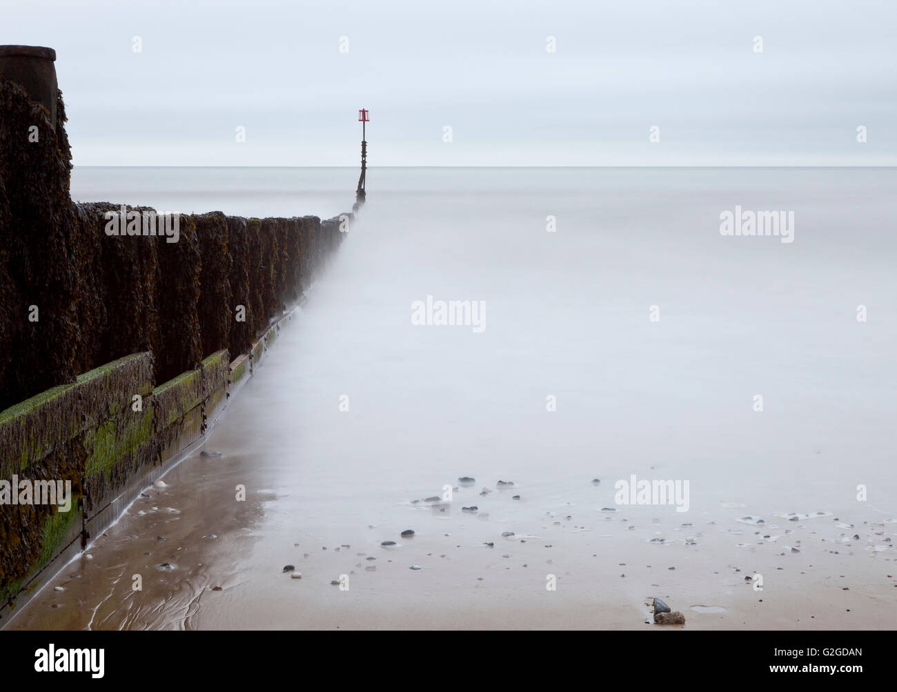 Groynes covered with seaweed, and waves merging into mist at Cromer ...