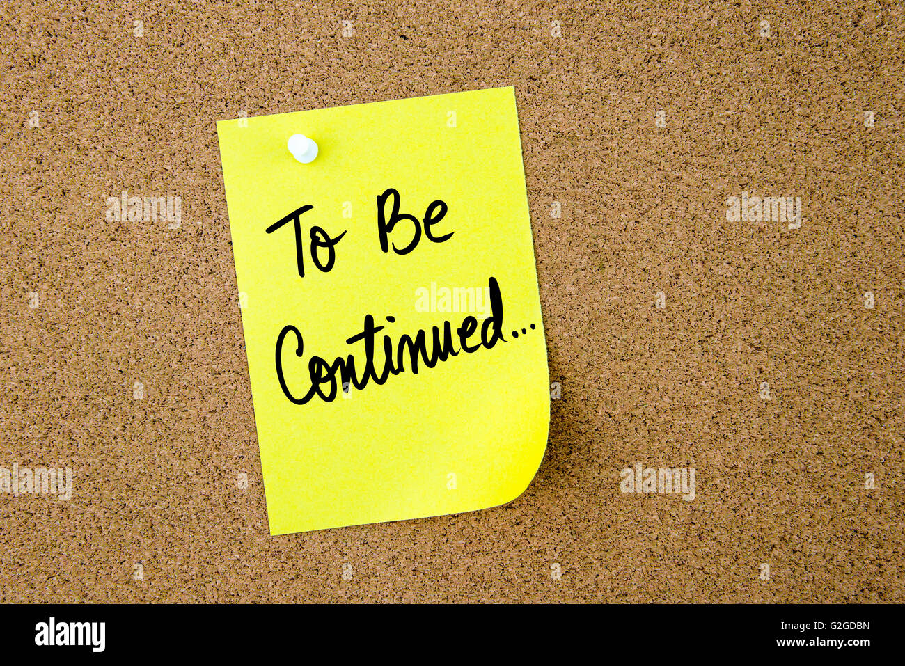 To Be Continued written on yellow paper note pinned on cork board with ...