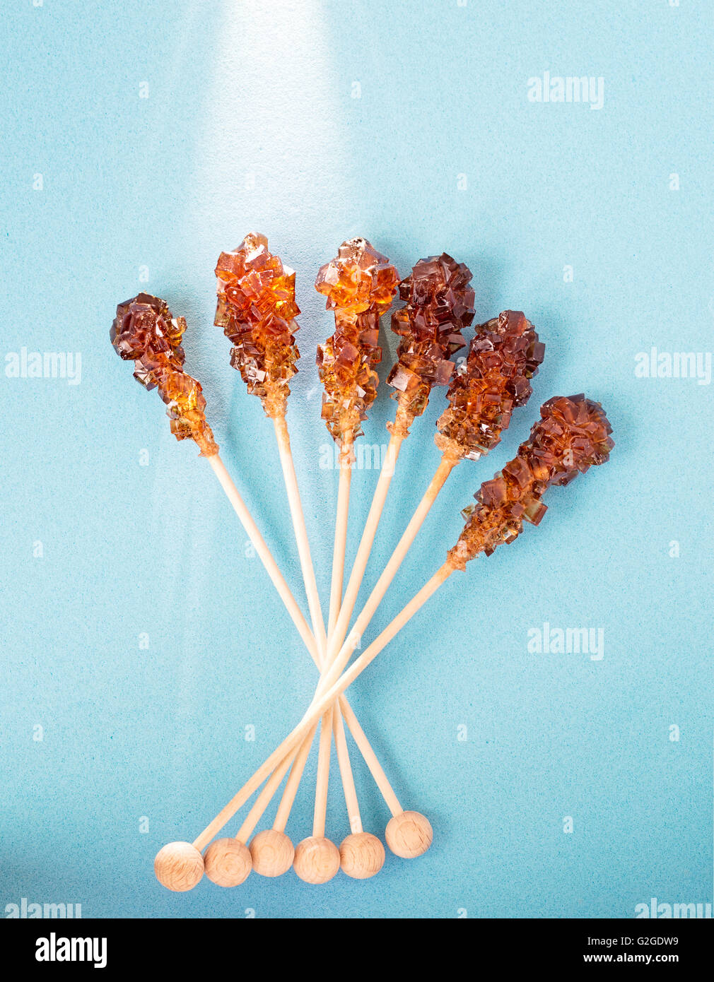 Top view of six brown sugar stirrers on a light blue background with a ...