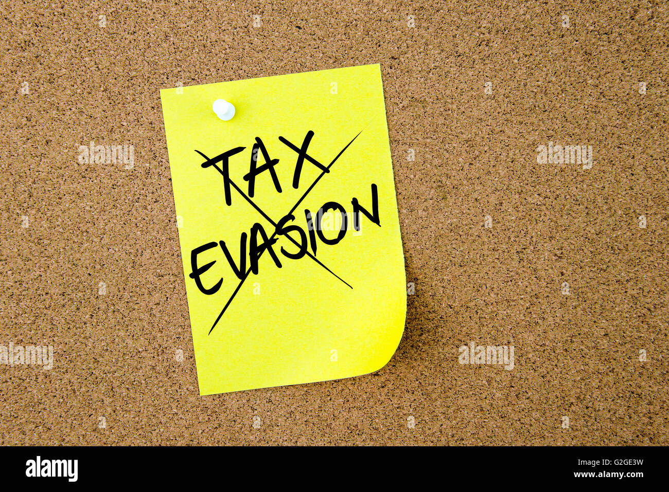 TAX EVASION crossed out written on yellow paper note pinned on cork ...