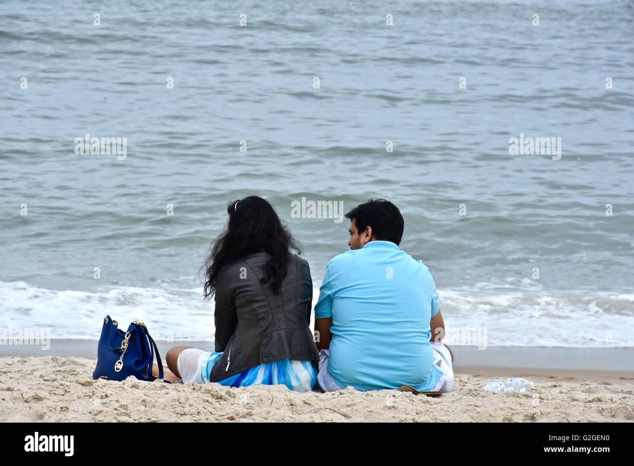 A romantic couple sitting on the beach while watching the ocean waves ...