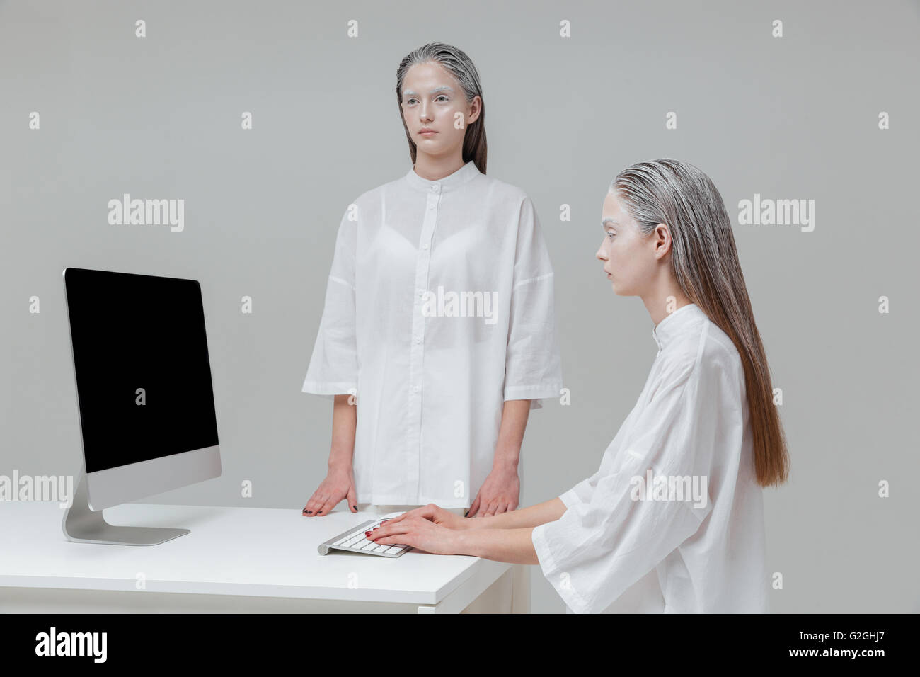 Two mysterious fashion girls using computer, pc Stock Photo - Alamy