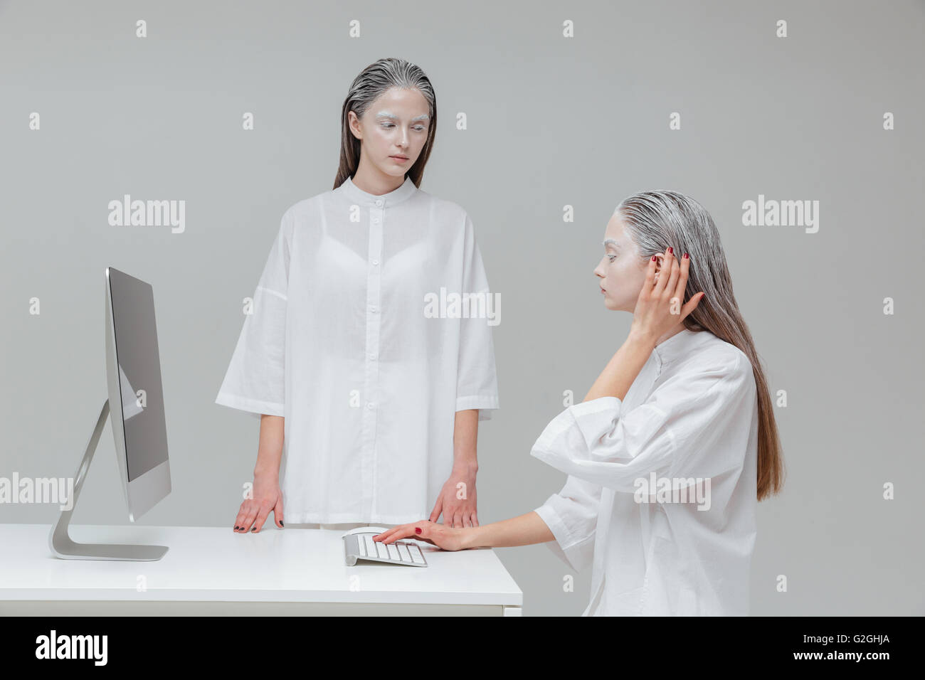 Two alien cosmic women using computer over gray background Stock Photo ...
