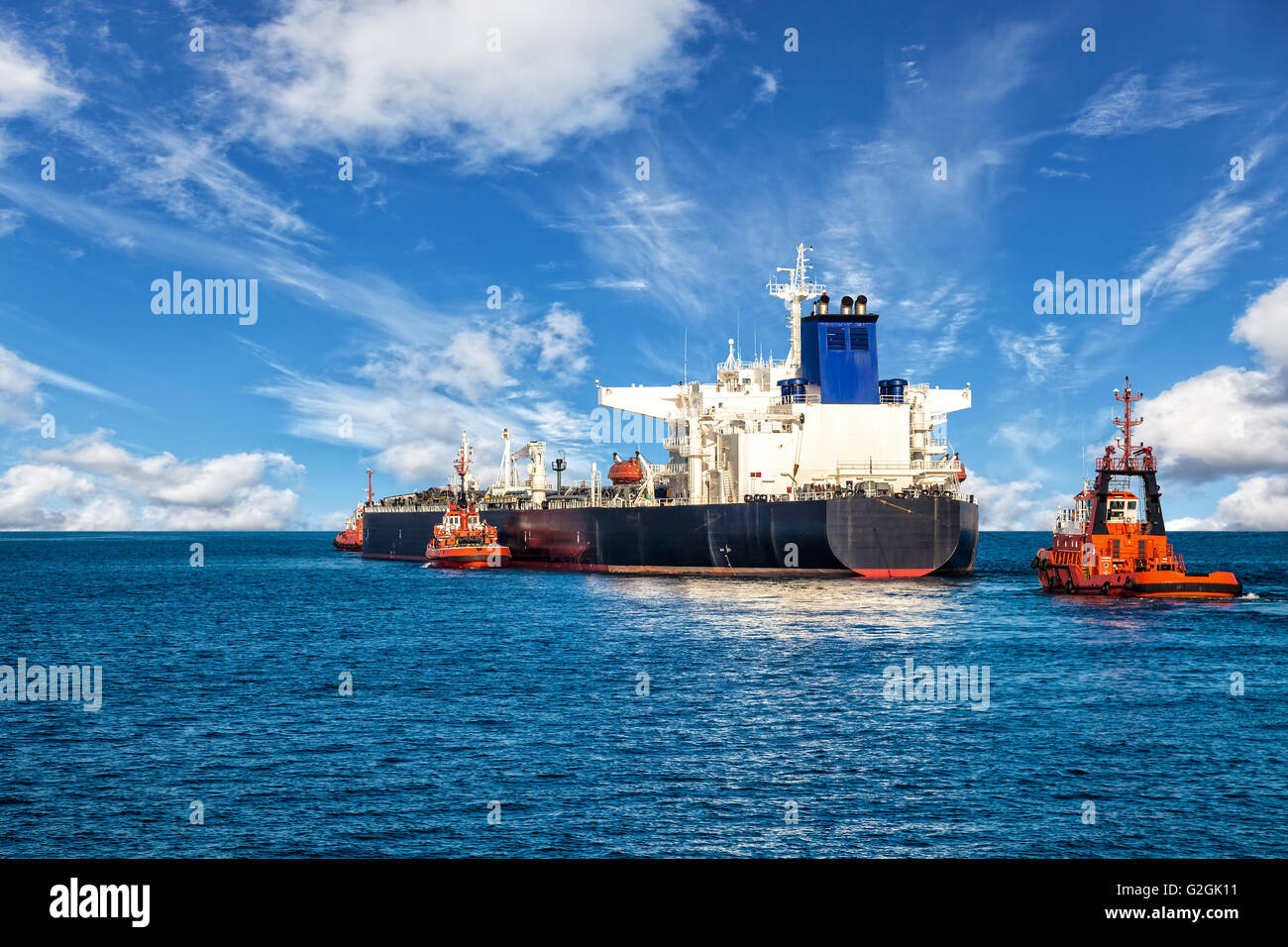 Tugboats towing a tanker ship at sea Stock Photo - Alamy