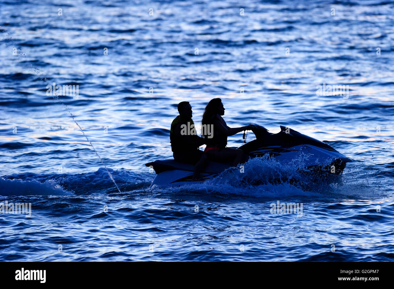 Jet ski people is a couple riding a jet ski silhouetted against the ...