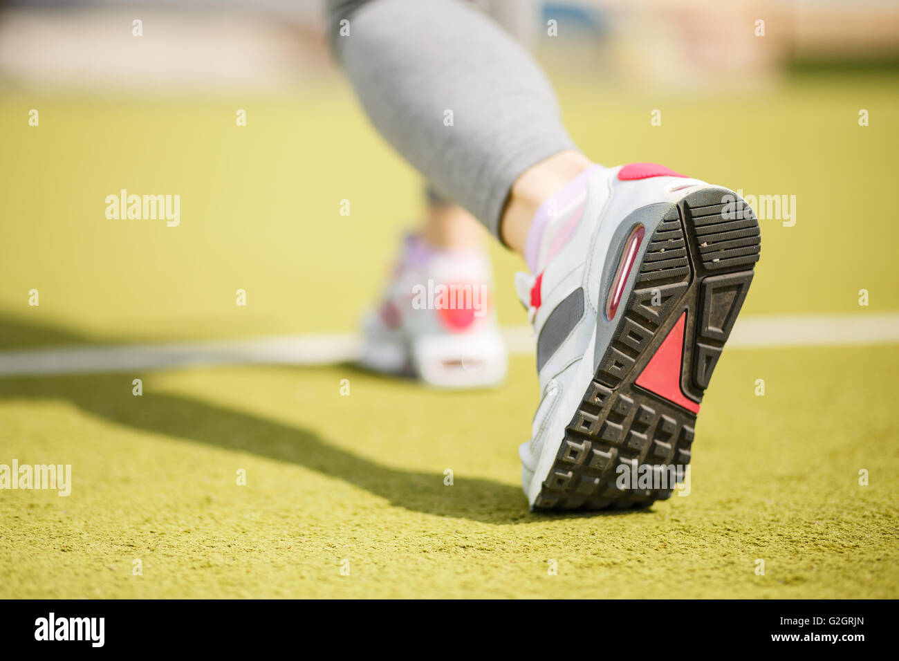 Sportswoman start running at the stadium. Female feet in trainers at ...