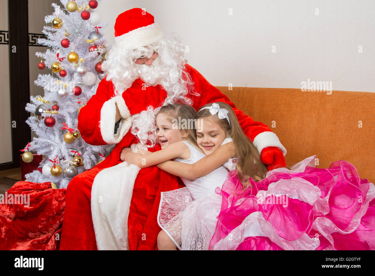 Two girls in beautiful dresses hug Santa Claus Stock Photo - Alamy