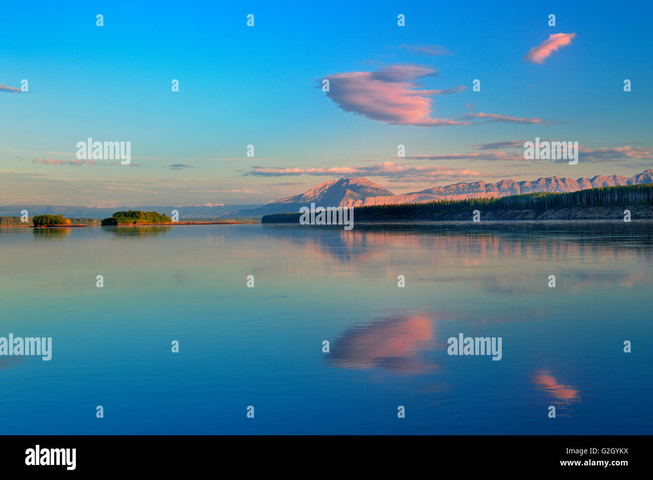 Clouds and Mackenzie Mountains at sunrise reflecting in the Liard River ...
