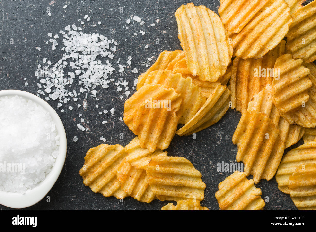 Crinkle cut potato chips on kitchen table. Tasty spicy potato chips ...