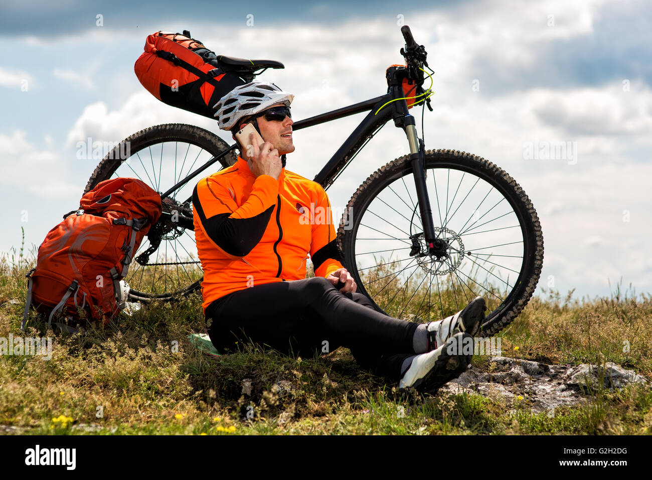 Young man sitting near the cycle on a green meadow Stock Photo - Alamy