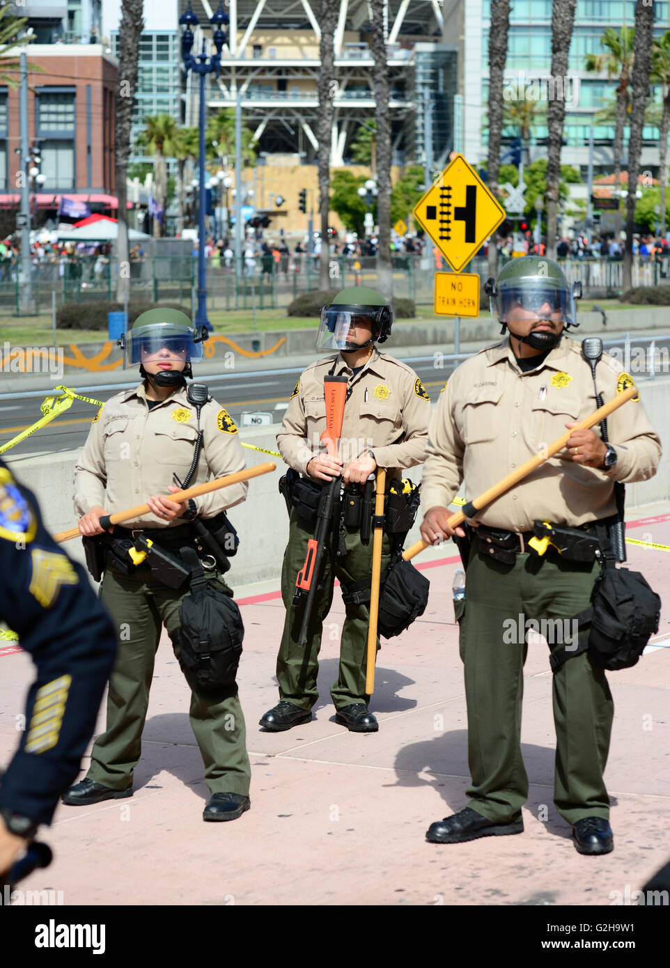 San Diego Police officers dressed in riot gear hold billy clubs and a ...