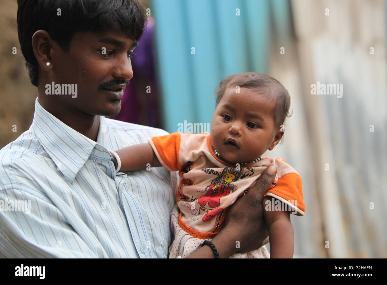 A portrait of a poor Indian father holding his little son, looking at ...