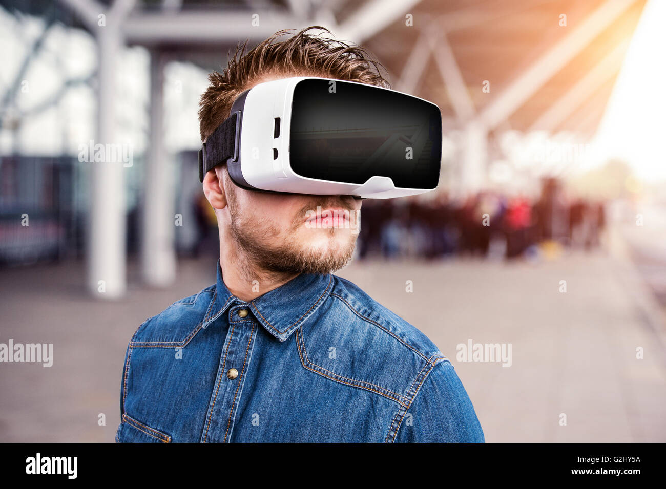 Hipster man in denim shirt wearing virtual reality goggles, standing at ...