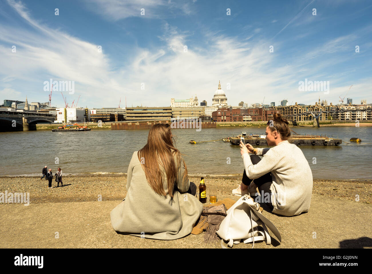 Two young women sitting and relaxing on the sandy shores of the River ...