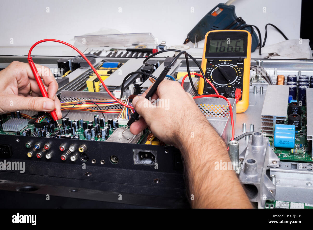 Electronics Repair service with red probe and capacitors on electronic ...