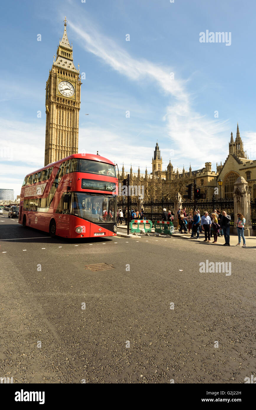 Modern red bus travels past Big Ben, Parliament Square in London during ...