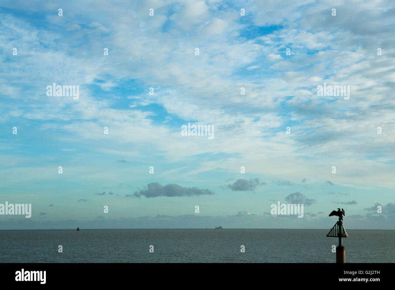 The horizon line with the sky and the ocean. A sign o the bottom right ...