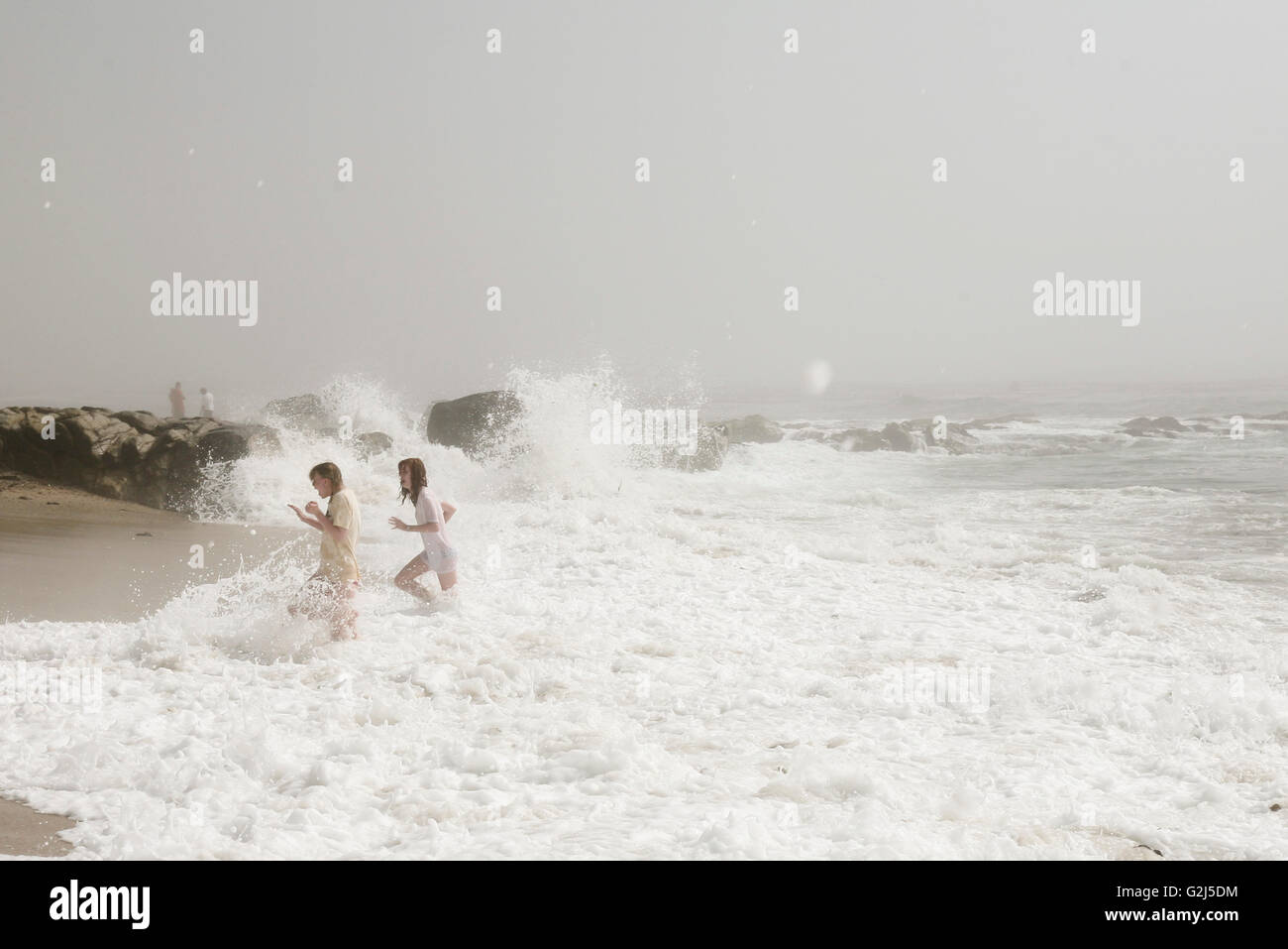 Two Young Woman Running in Waves Stock Photo - Alamy
