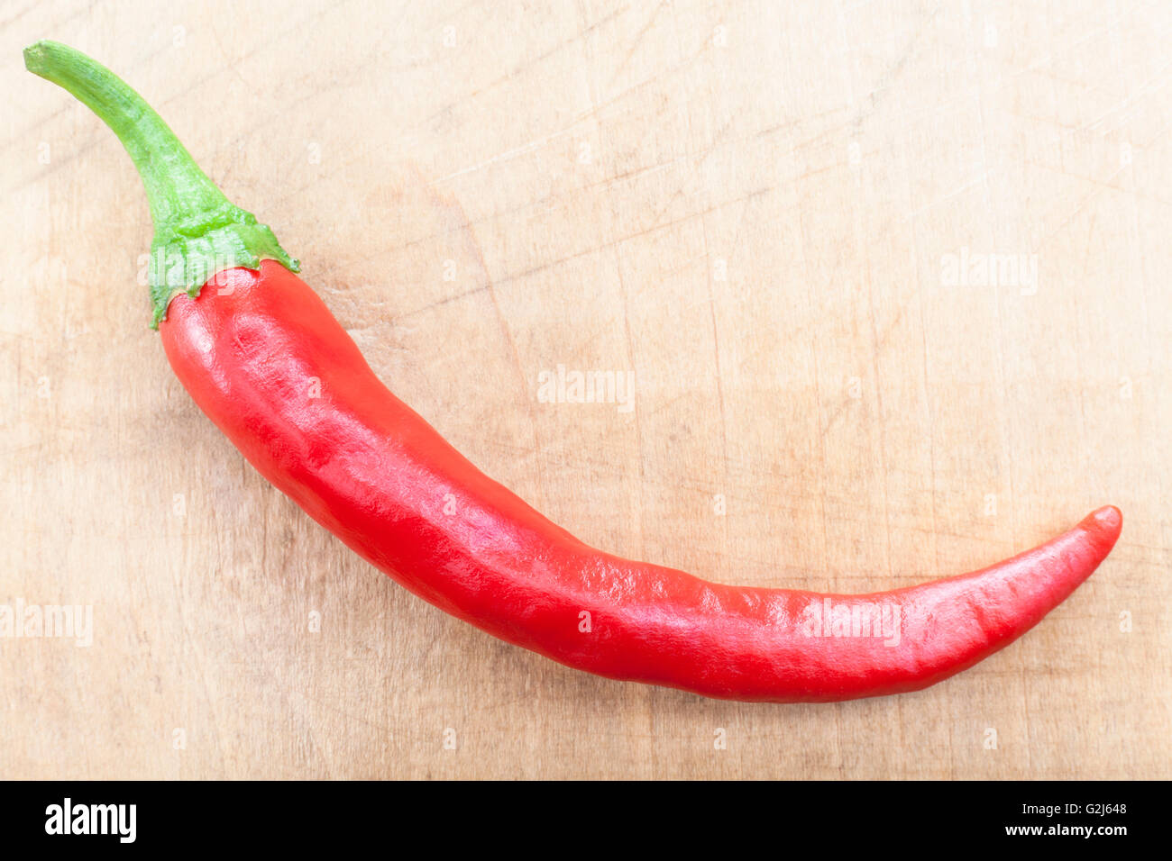 Single Red Hot Chili pepper on brown wood background Stock Photo - Alamy