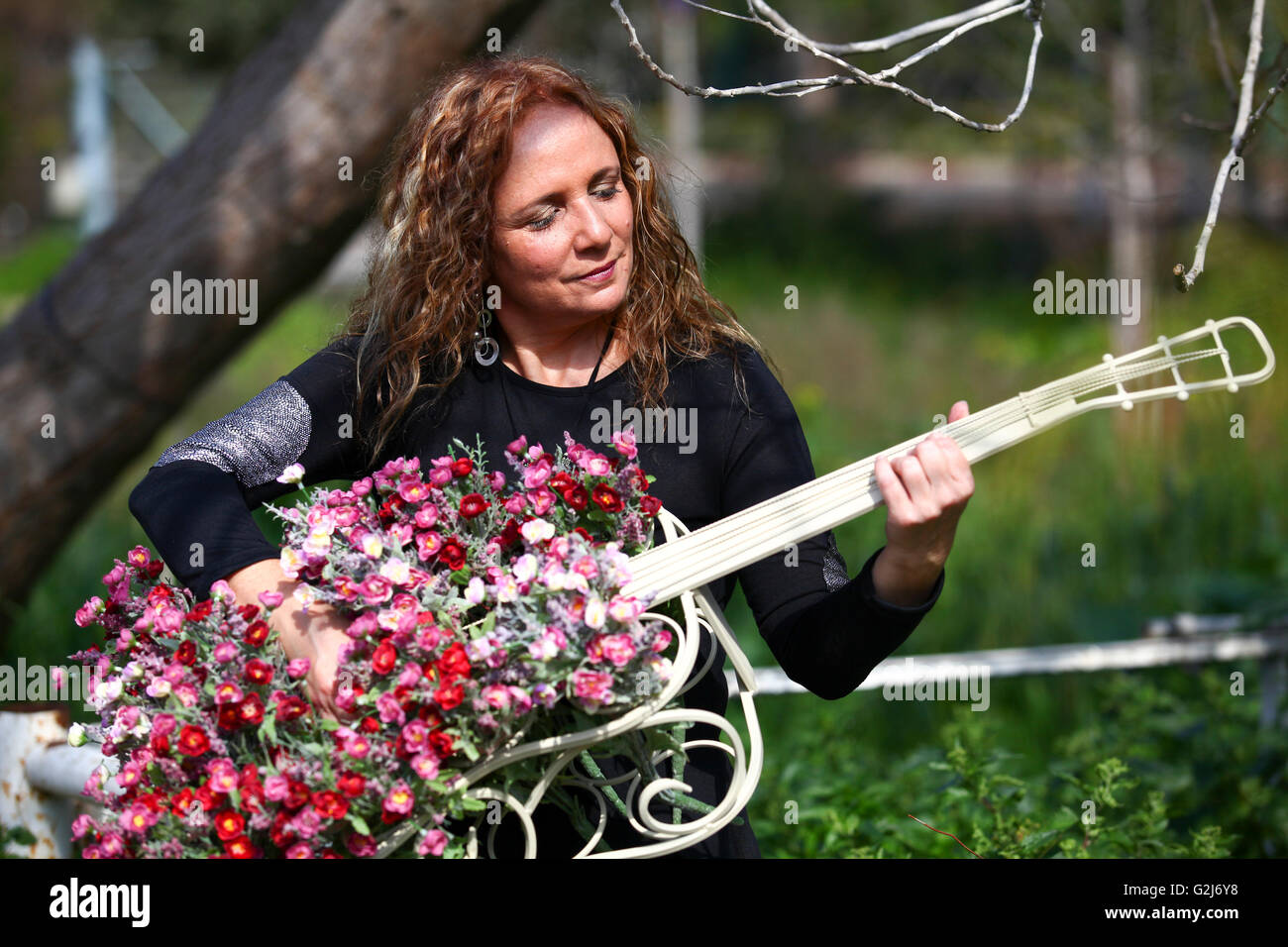 Woman with a guitar shaped flowerpot in her garden Stock Photo - Alamy