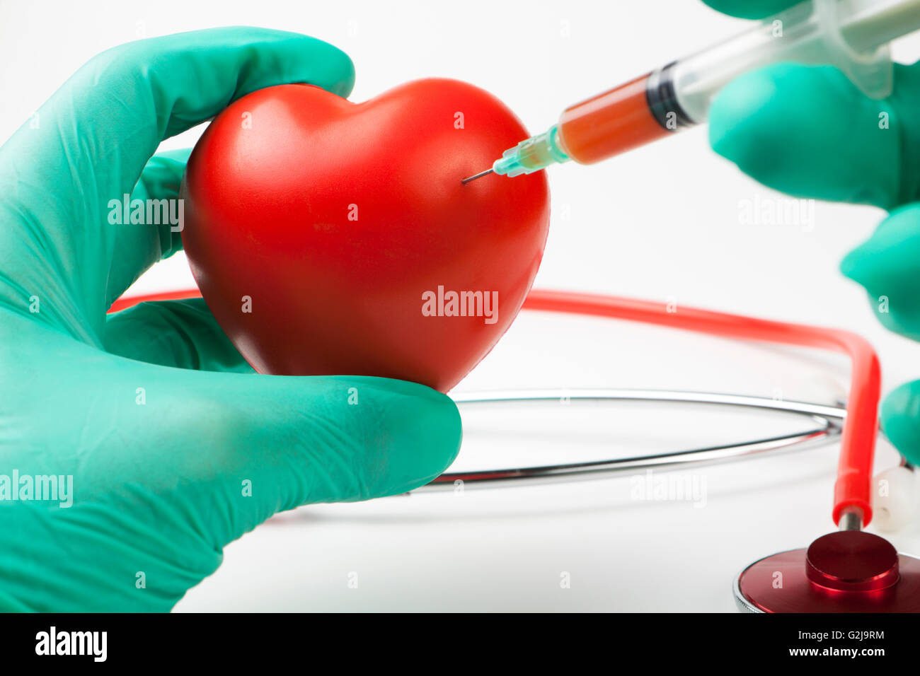 injecting blood int o a big red heart by two hands with green gloves on ...