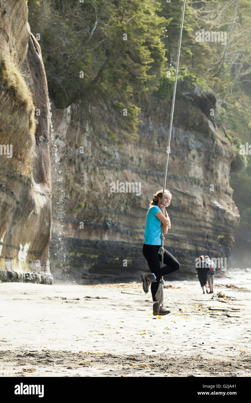 A young woman swings on a rope swing at Mystic Beach along the Juan de ...