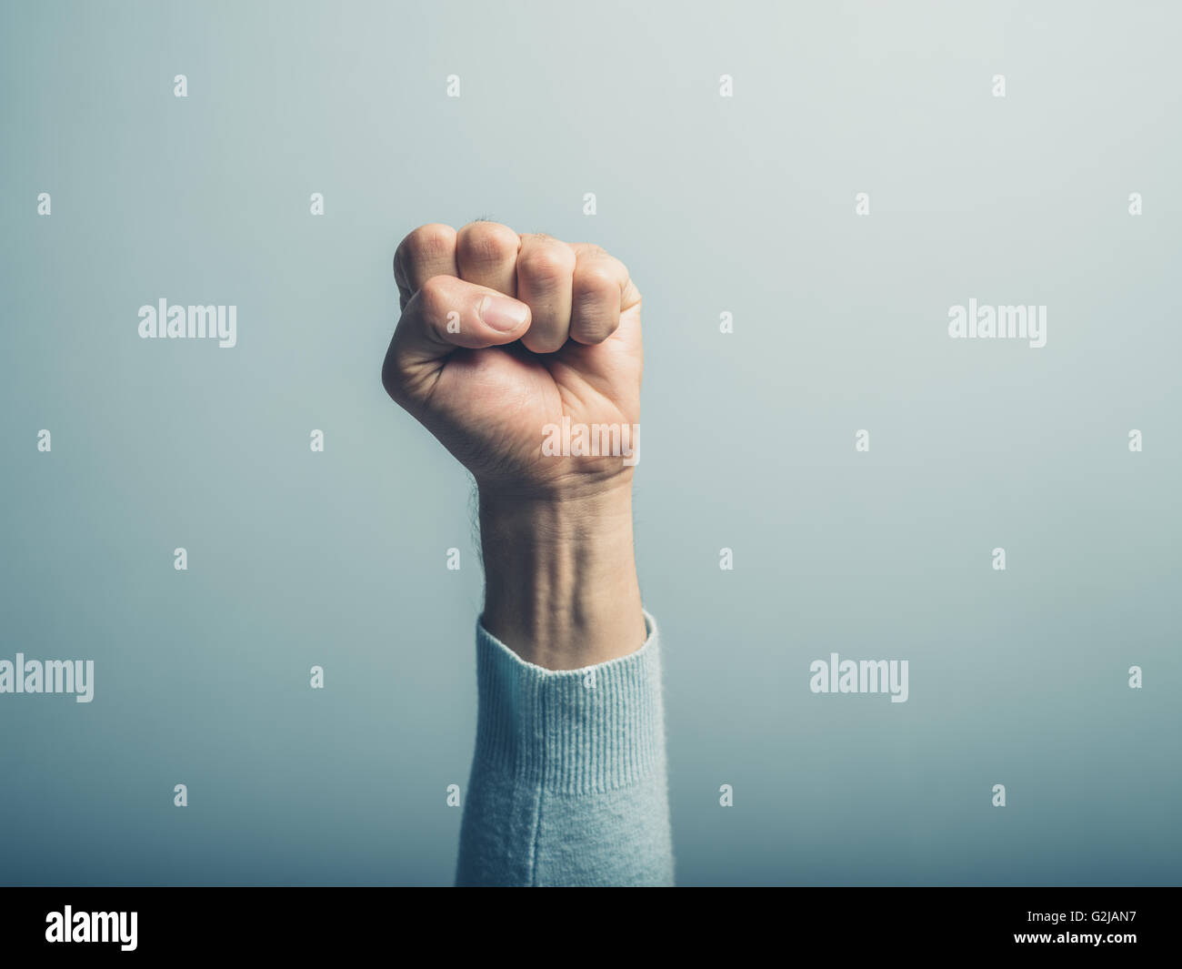 A clenched male fist is up in the air Stock Photo - Alamy